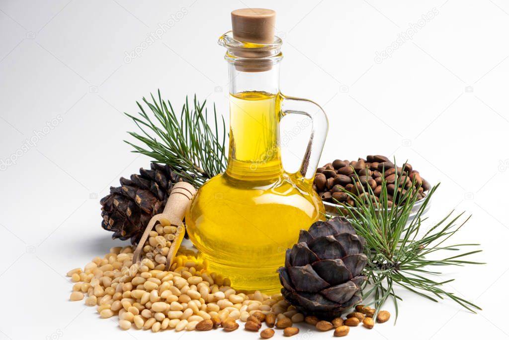Aceite de piñones con piñones pelados y conos de pino sobre blanco 2023