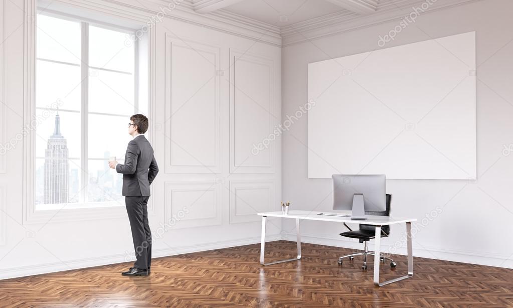 Businessman lookinng through window, table with computer in big hall ...