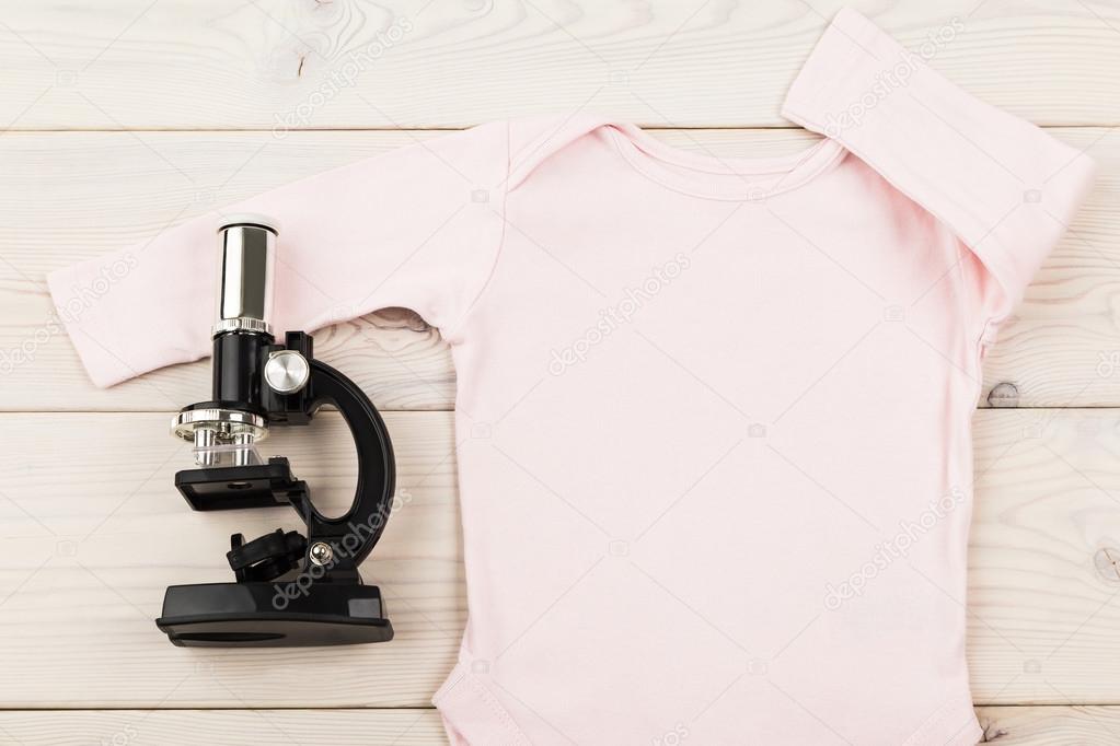 Future occupation concept. Pink baby girl outfit and microscope on ...