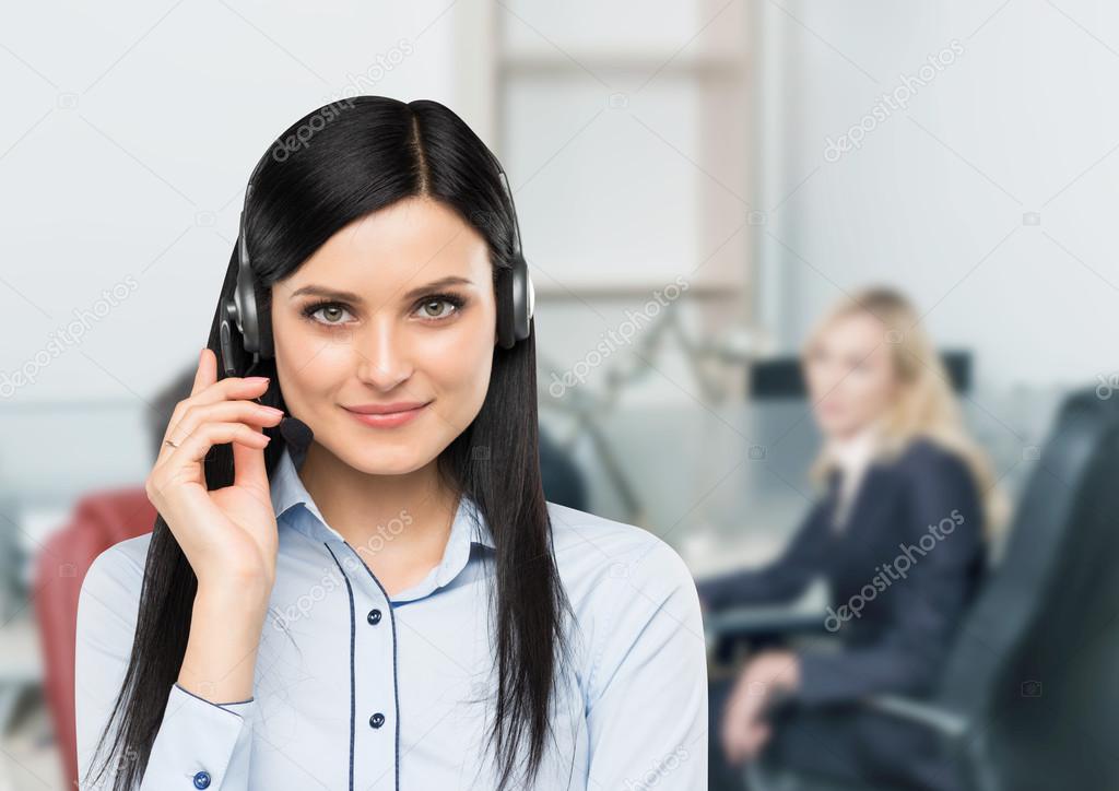 Front view of the smiling brunette support phone operator with headset ...