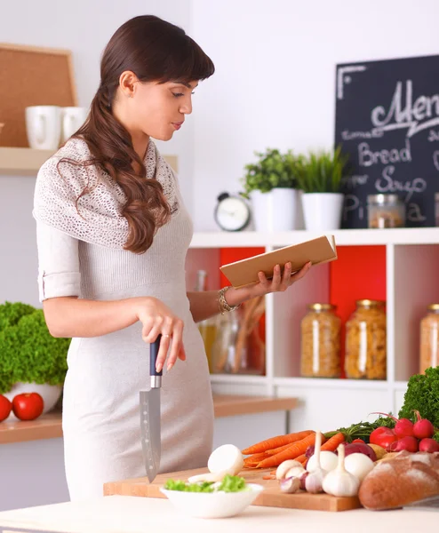Young woman reading cookbook in the kitchen, looking for recipe - Stock ...