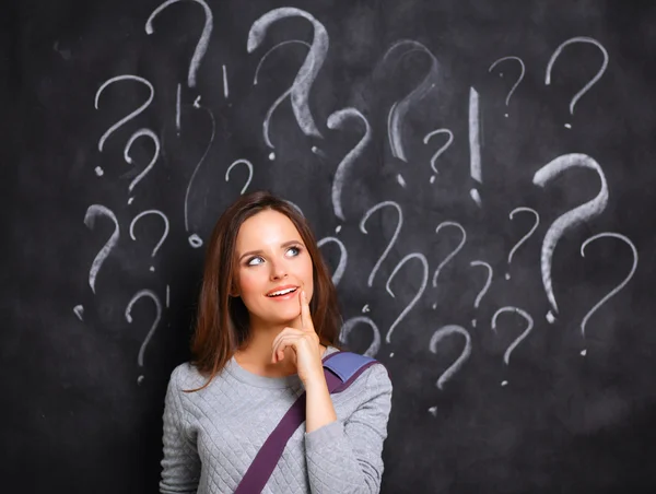 Young woman with doubtful expression and question marks over her head ...