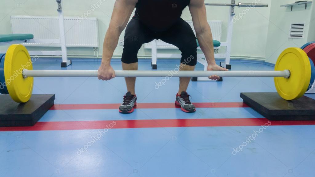 A man performs an exercise with a barbell. Young weightlifter in the ...