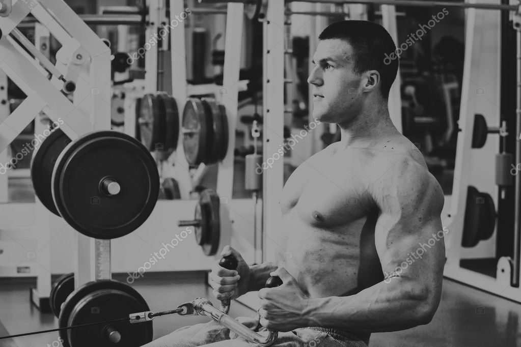 Muscular man in the gym. Work on the arm muscles. Training on a ...