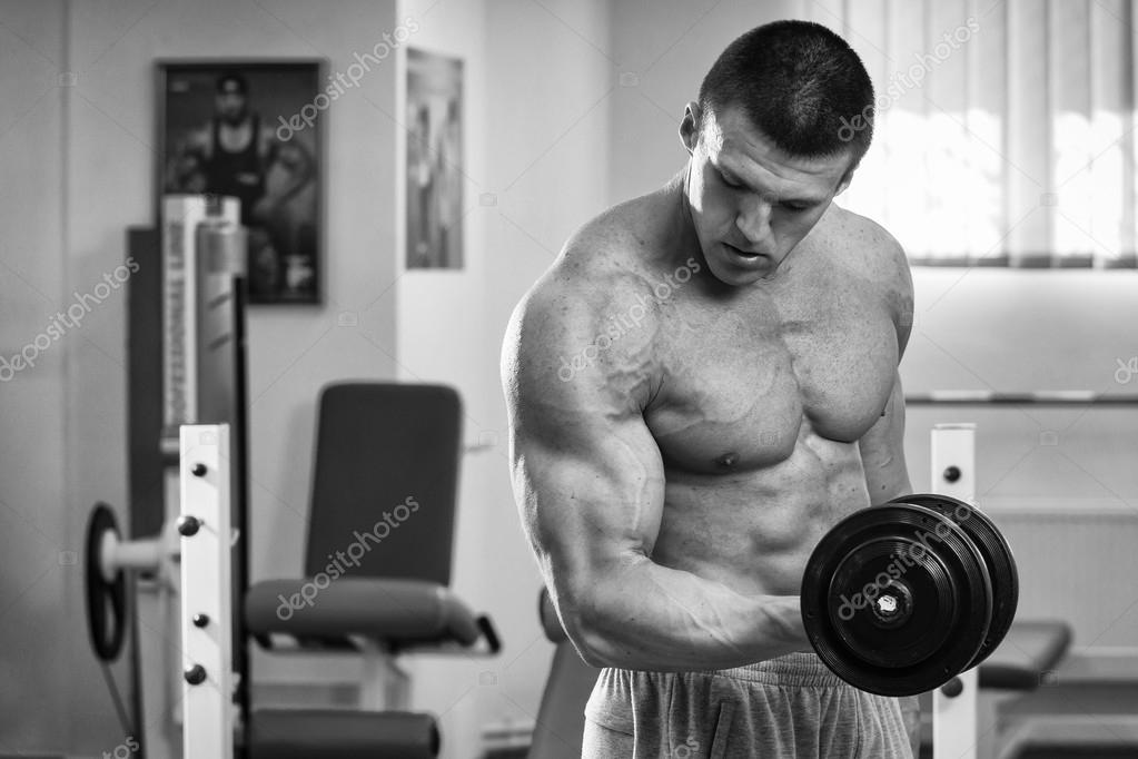 Bodybuilder makes exercises with dumbbells — Stock Photo © aallm #64447807