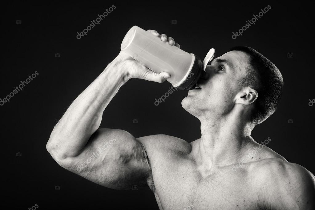 Muscular man with a shaker in hands against a dark background — Stock ...