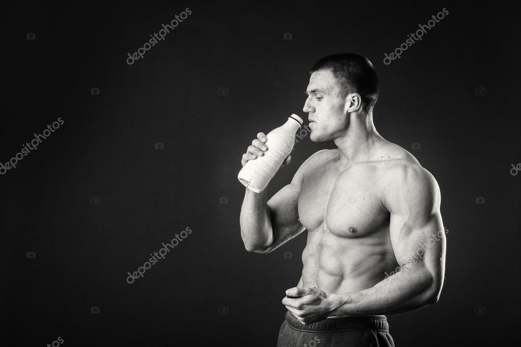 Man bodybuilder posing on gray background Man is holding a shaker for ...