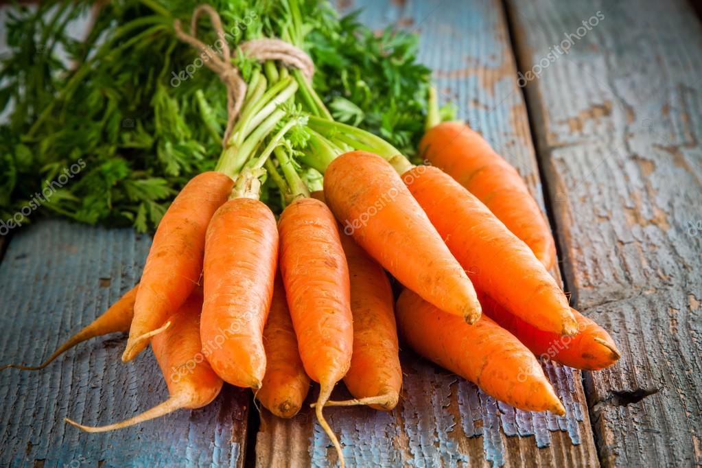 Fresh carrots bunch on wooden background Stock Photo by ©nblxer 64448965