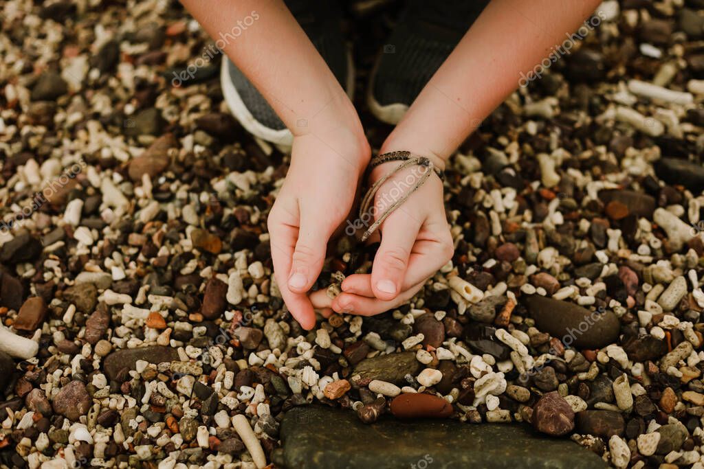 Un joven se agacha en la playa en el paraíso recogiendo conchas 2022