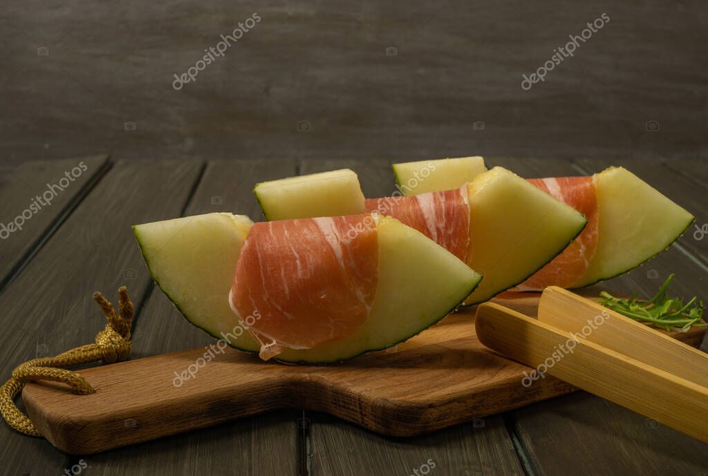 melón jugoso con jamón comida típica de verano sobre fondo oscuro 2022