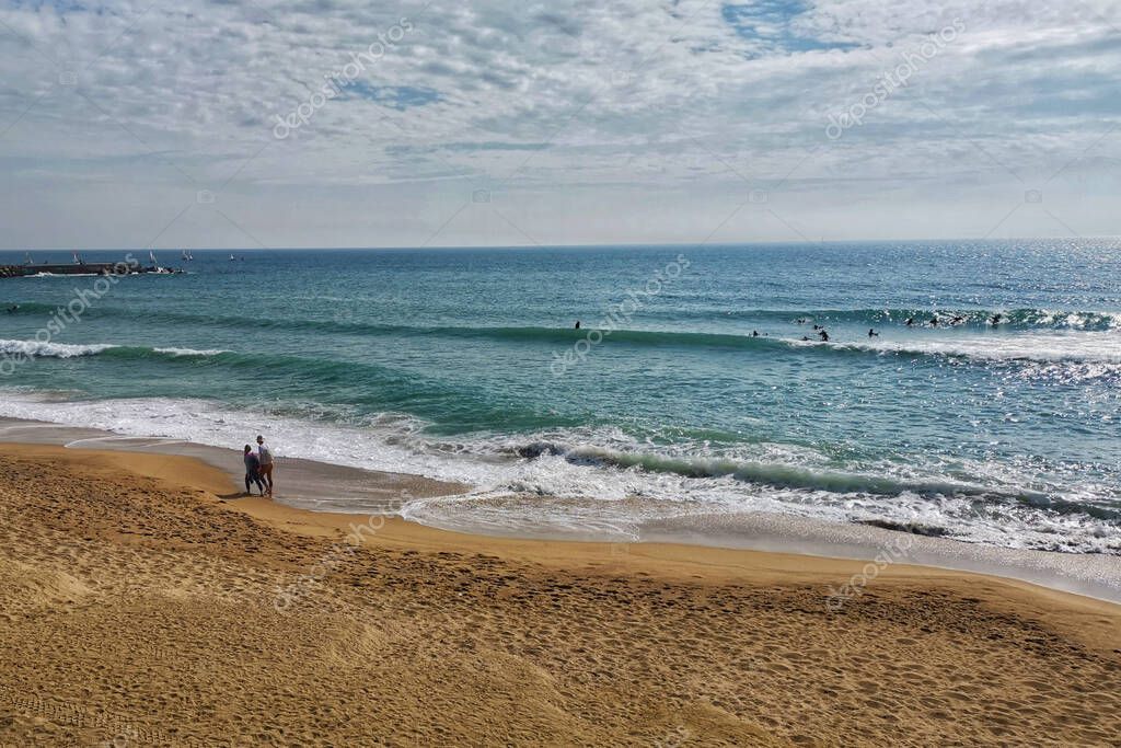 Un día soleado brillante en una hermosa playa con gente nadando en el ...