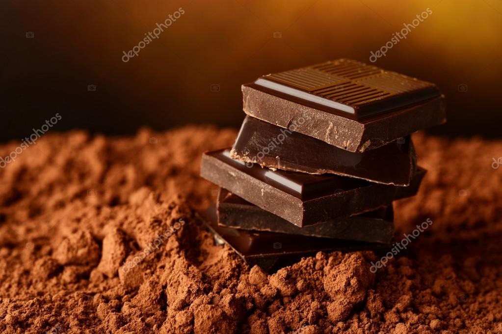 Heap of blocks of chocolate on cocoa powder Stock Photo by ©dla4 65824215
