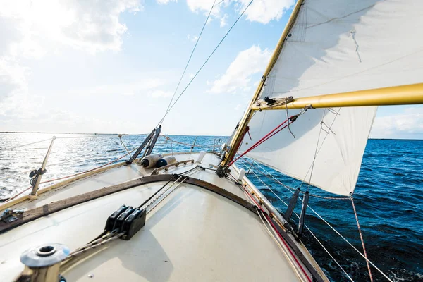 Sloop rigged yacht sailing on a clear day. A view from the deck to the ...