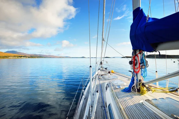 Sloop rigged modern yacht with wooden teak deck sailing near the shore ...