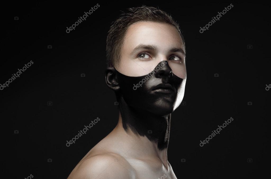 Handsome young guy with make-up with black mask on her face isolated on ...