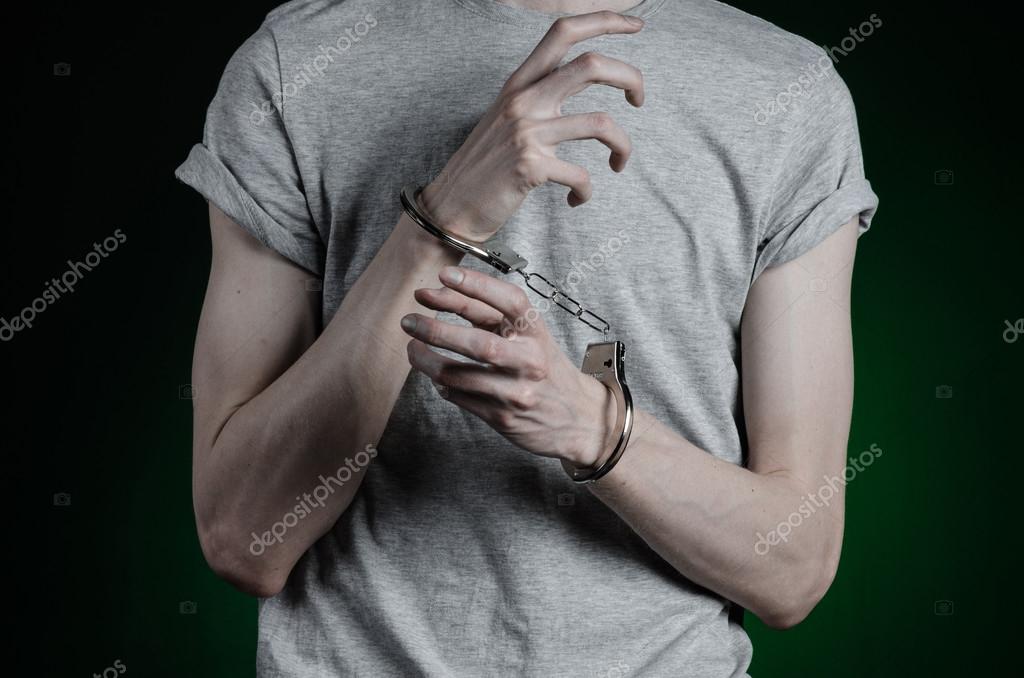 Prison and convicted topic: man with handcuffs on his hands in a gray T ... Prison and convicted topic: man with handcuffs on his hands in a gray T ...