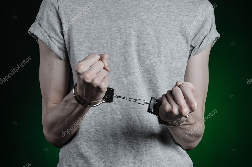 Prison and convicted topic: man with handcuffs on his hands in a gray T ... Prison and convicted topic: man with handcuffs on his hands in a gray T ...