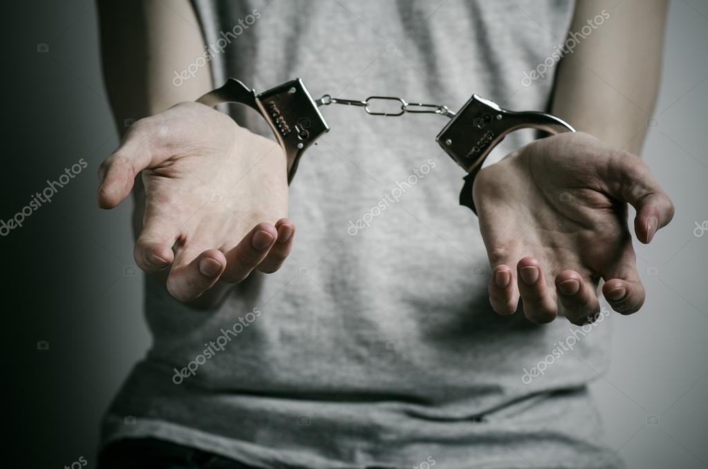 Prison and convicted topic: man with handcuffs on his hands in a gray T ... Prison and convicted topic: man with handcuffs on his hands in a gray T ...