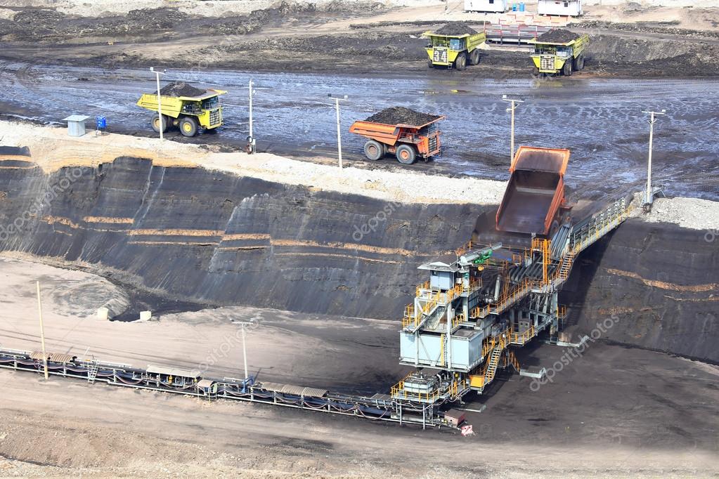 Heavy construction tipper trucks dump coal to the conveyor at co Stock ...