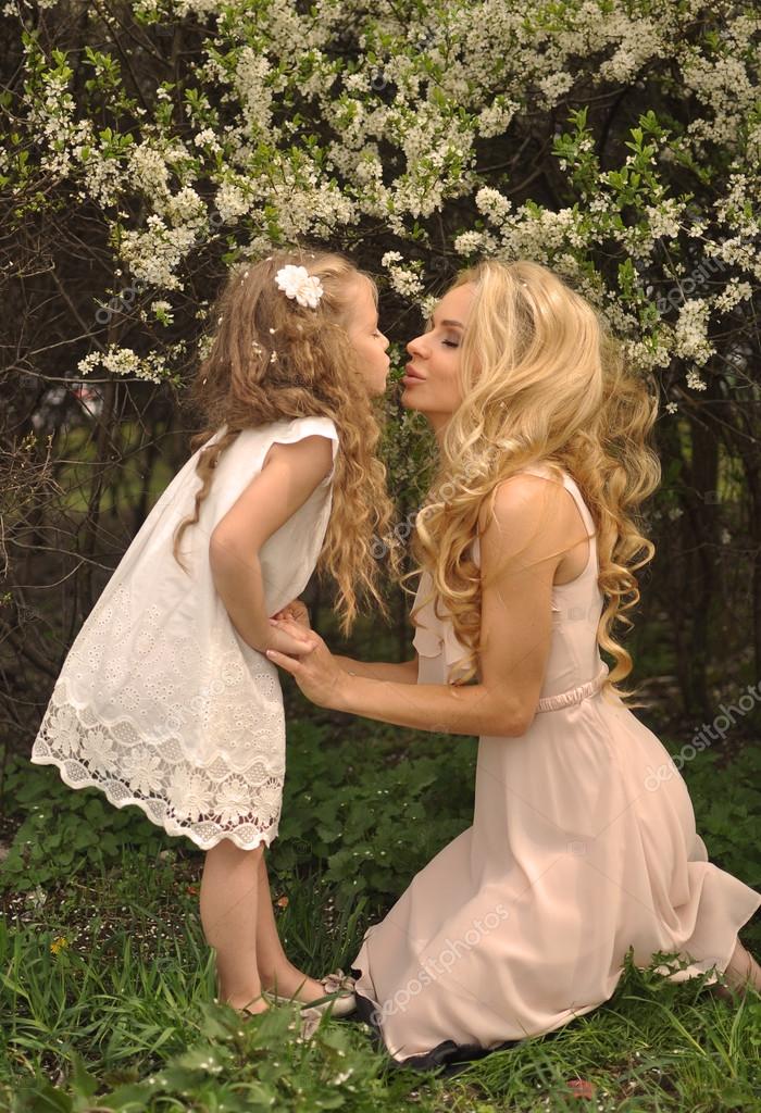A Beautiful Blond Mother With A Small Daughter Girl Snuggling On Nature