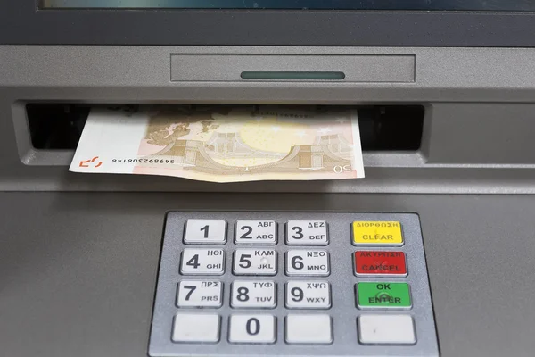 People stand in a queue to use the ATMs of a bank. Person receiv ...