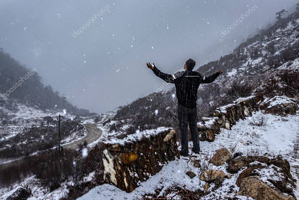 joven disfrutando de la caída de nieve en las montañas del himalaya en ...