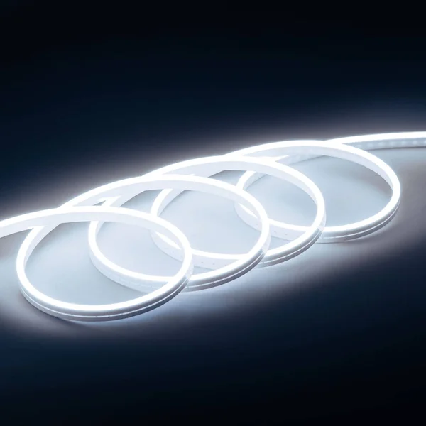 Flexible cold white led tape neon glowing on black background. - Stock ...