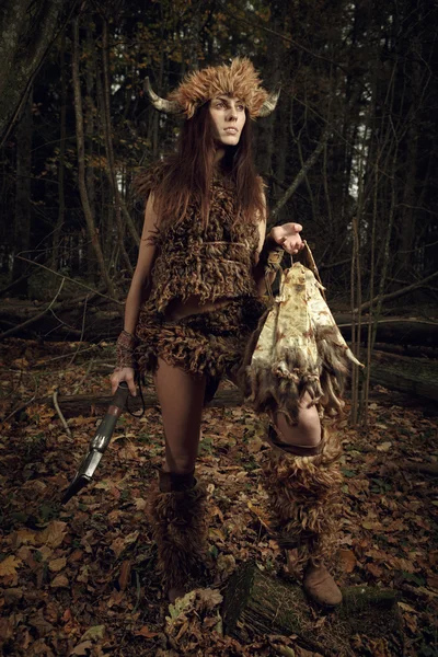 Ancient woman hunter in the forest with an ax in his hand. Histo ...