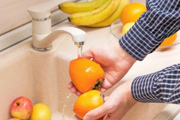 Manos lavando caqui y limón. Lavado de frutas y alimentos en el ...