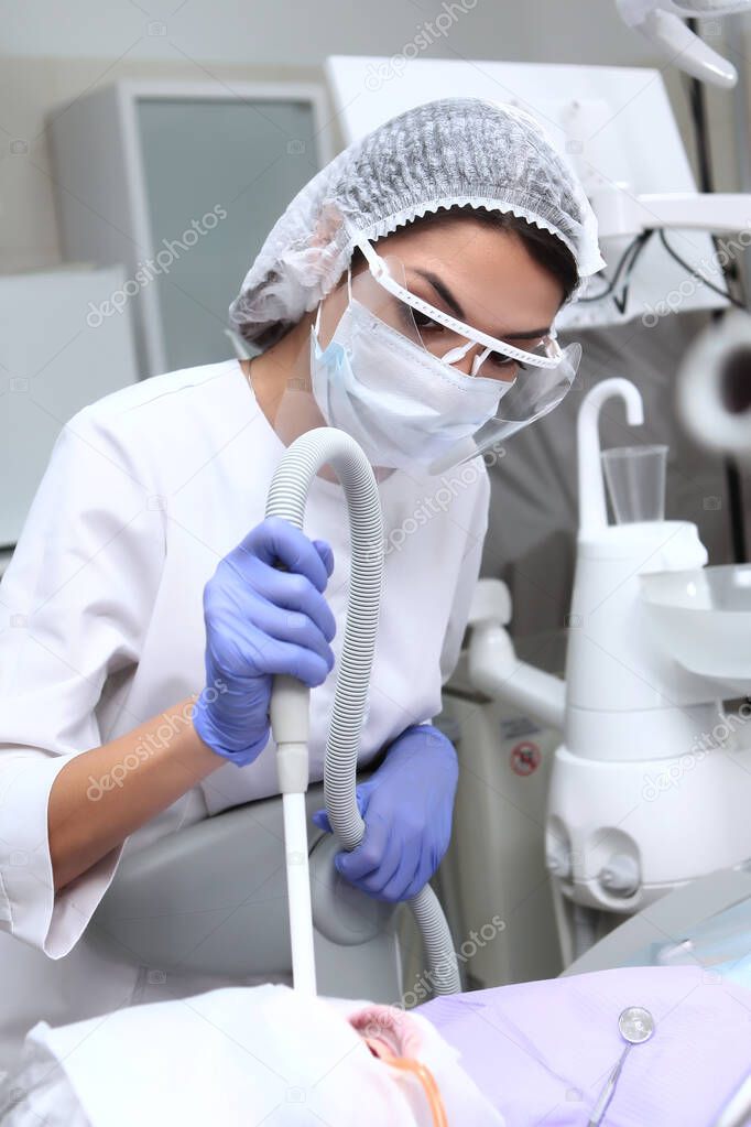 Asistente dental en el trabajo. El asistente sostiene una bomba de ...