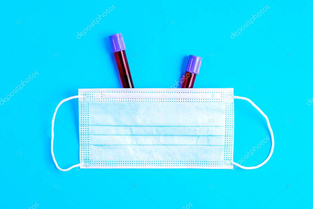 Mascarilla protectora y tubos de ensayo con sangre sobre fondo azul ...