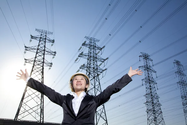 Businesswoman in front of power lines with arms oustretched - Stock ...
