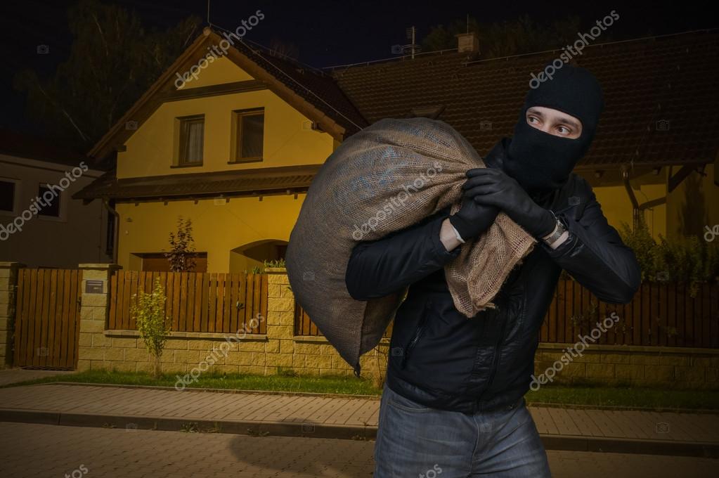 Masked robber or burglar robbed house at night and runs away wit Stock ...