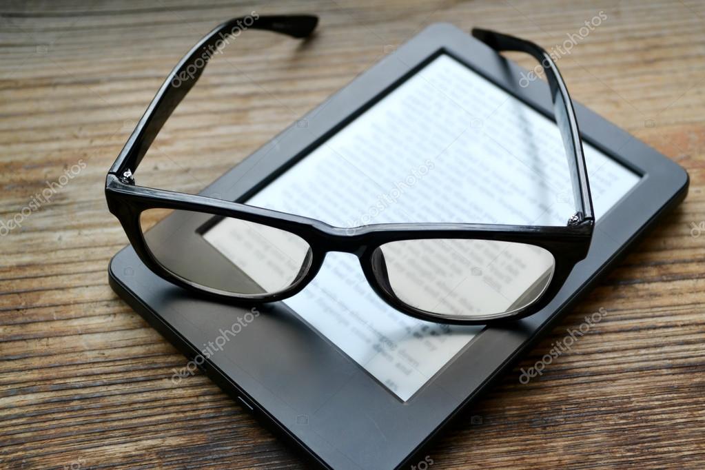 Black ereader with retro glasses on wooden table Stock Photo by ...