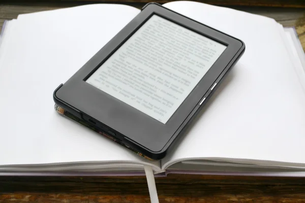 Black ereader with an old notebook in leather cover on wooden table ...