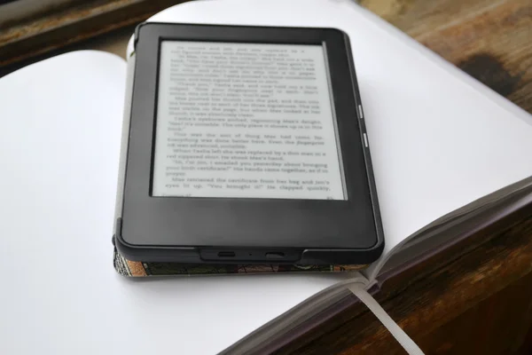 Black ereader with an old notebook in leather cover on wooden table ...