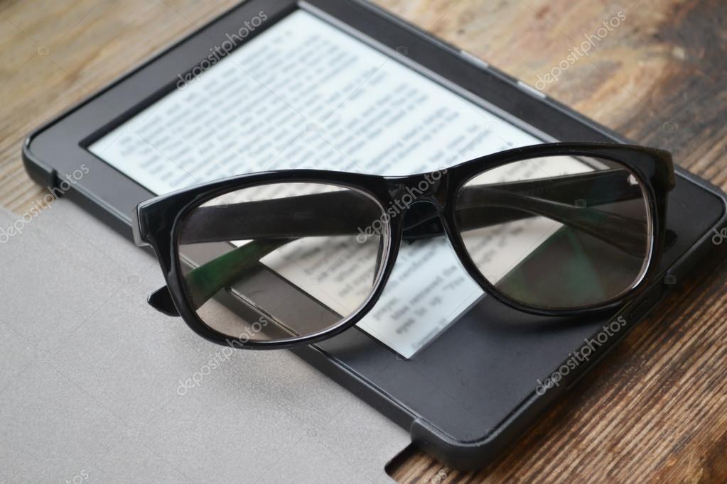 Black ereader with retro glasses on wooden table Stock Photo by ...