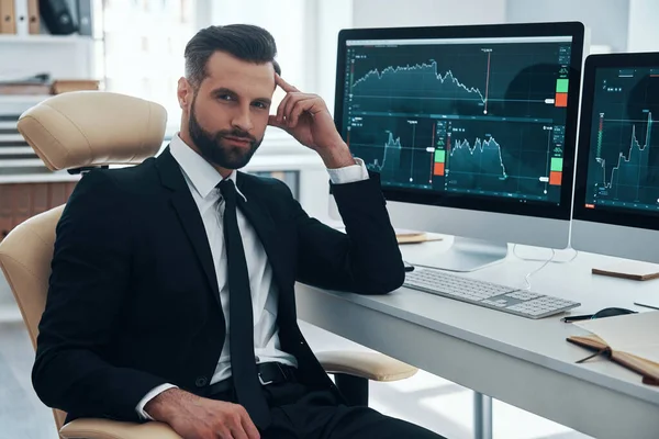 Good looking young man in formalwear looking at camera while working in ...
