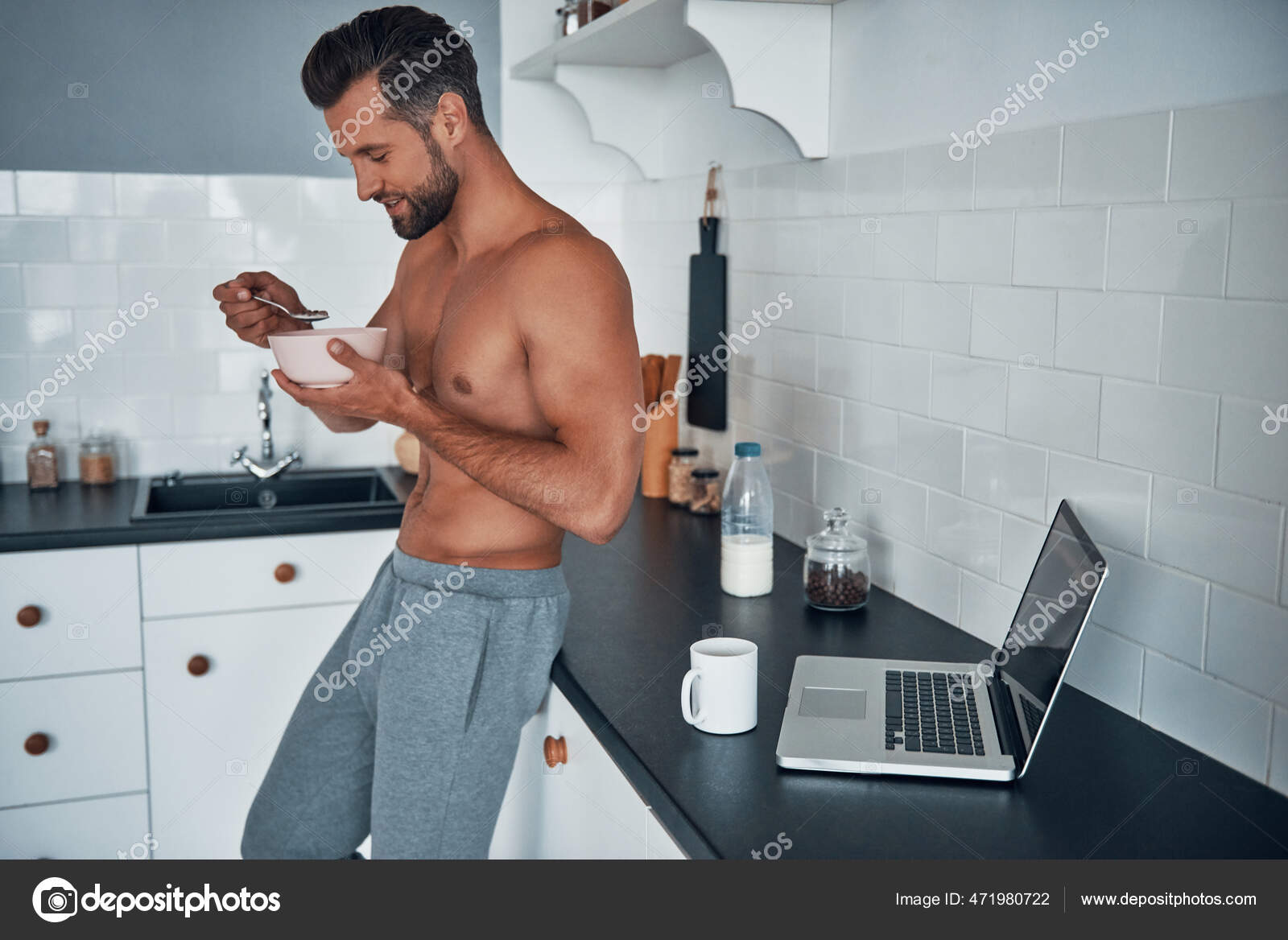 Handsome young shirtless eating breakfast while standing at home ...
