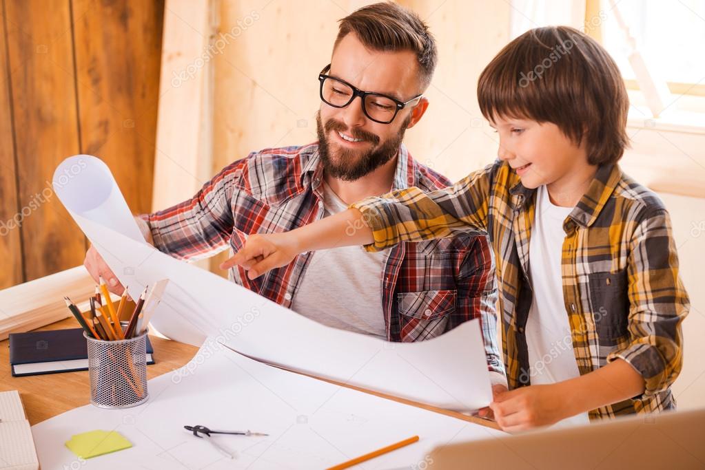 Boy and man holding blueprint Stock Photo by ©gstockstudio 74125695