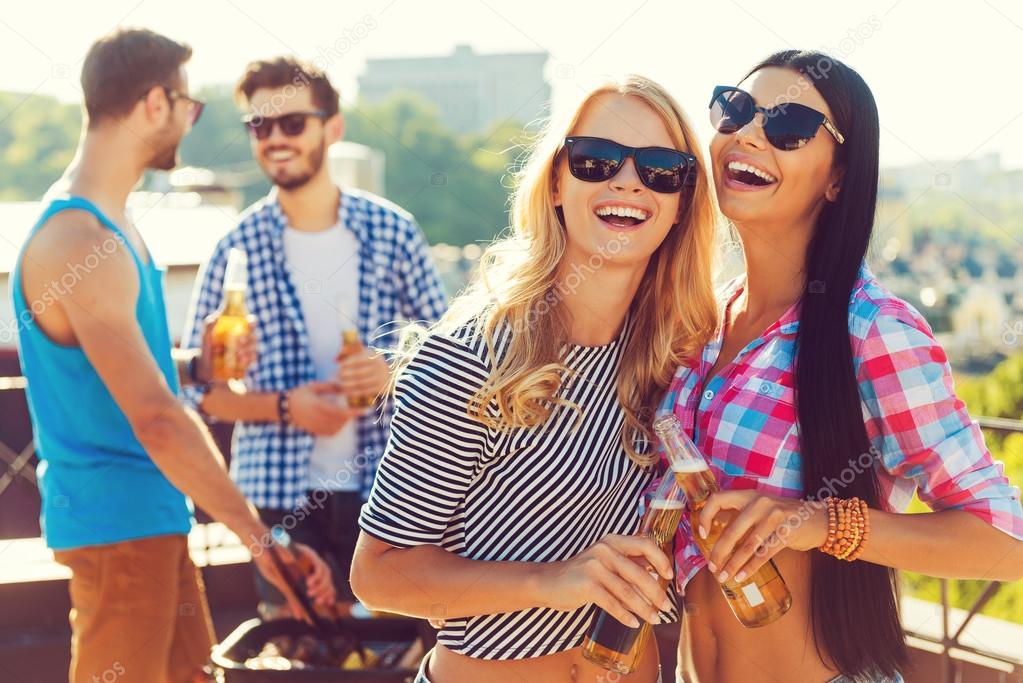 Women clinking bottles with beer Stock Photo by ©gstockstudio 80946520