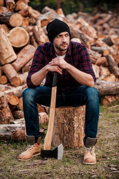 Thoughtful young forester sitting on log - Stock Image - Everypixel