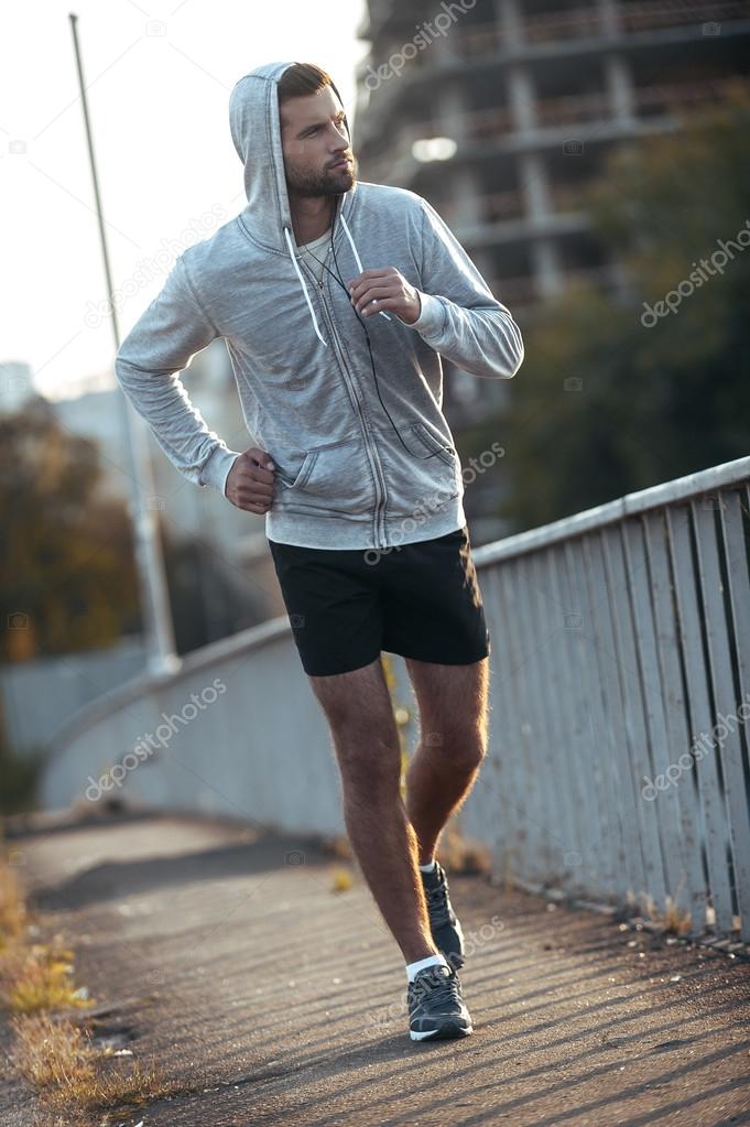 Young man running along road Stock Photo by ©gstockstudio 84975266