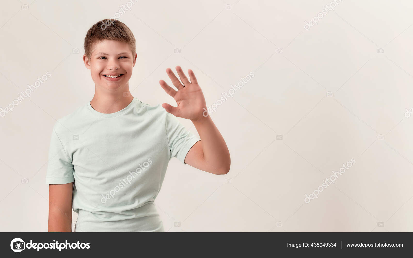 Happy disabled boy with Down syndrome smiling and waving at camera ...