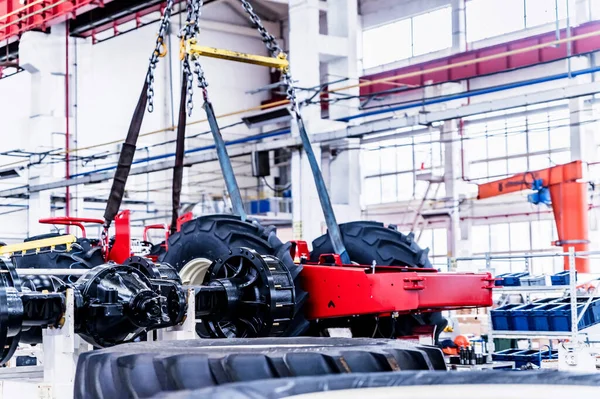 Big tractor wheels installation at assembly room at industrial plant ...