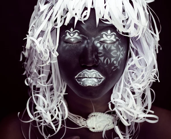 Creative makeup like Ethiopian mask, white pattern on black face close ...