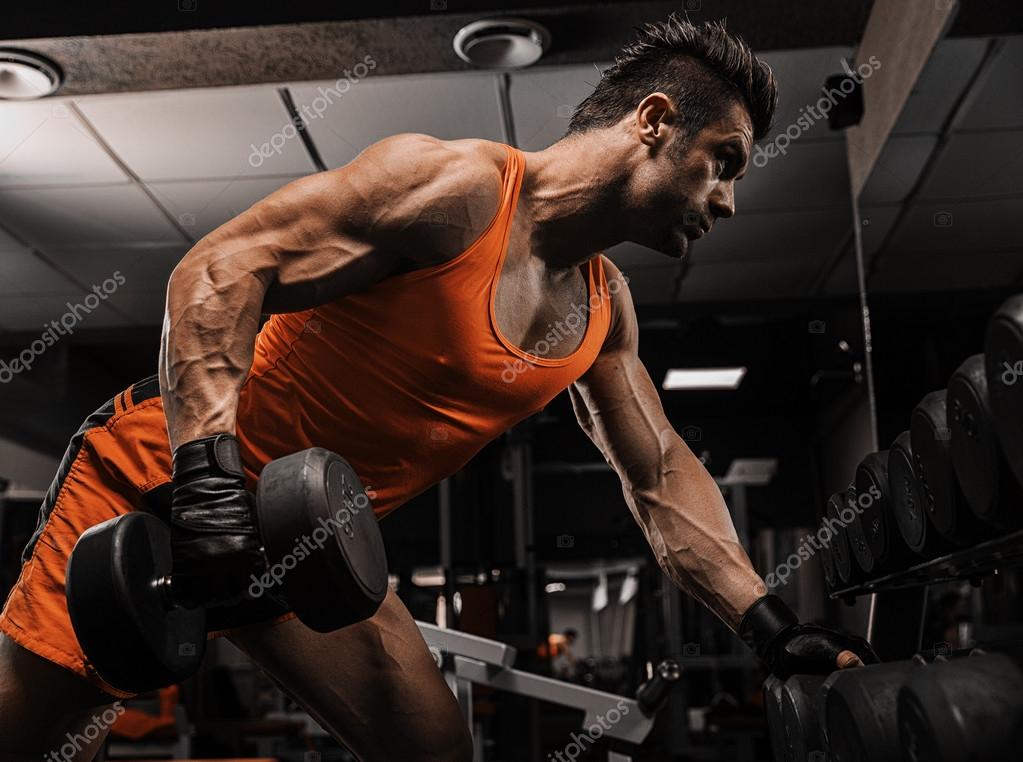 Very power athletic guy standing with barbell, workout in the gy Stock ...