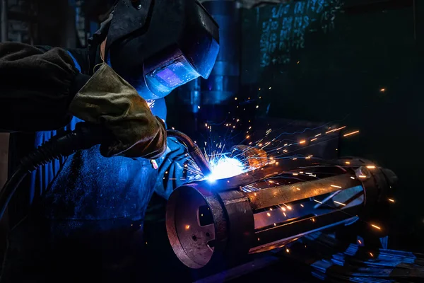 Side view of welder in protective helmet welding metal detail with ...