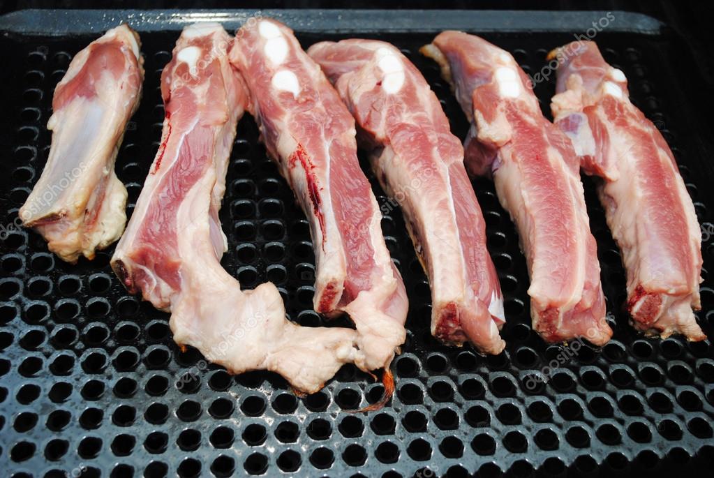 Riblets de cerdo fresco cocinando en una parrilla de verano 2023