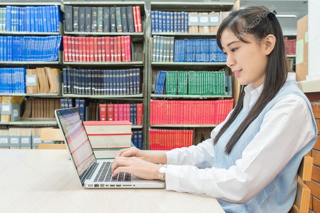 Asian female student with laptop and books working in a high sch ...